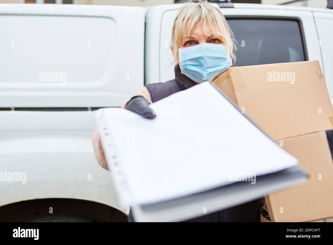 Parcel carrier of a delivery service wears a face mask because of Covid ...