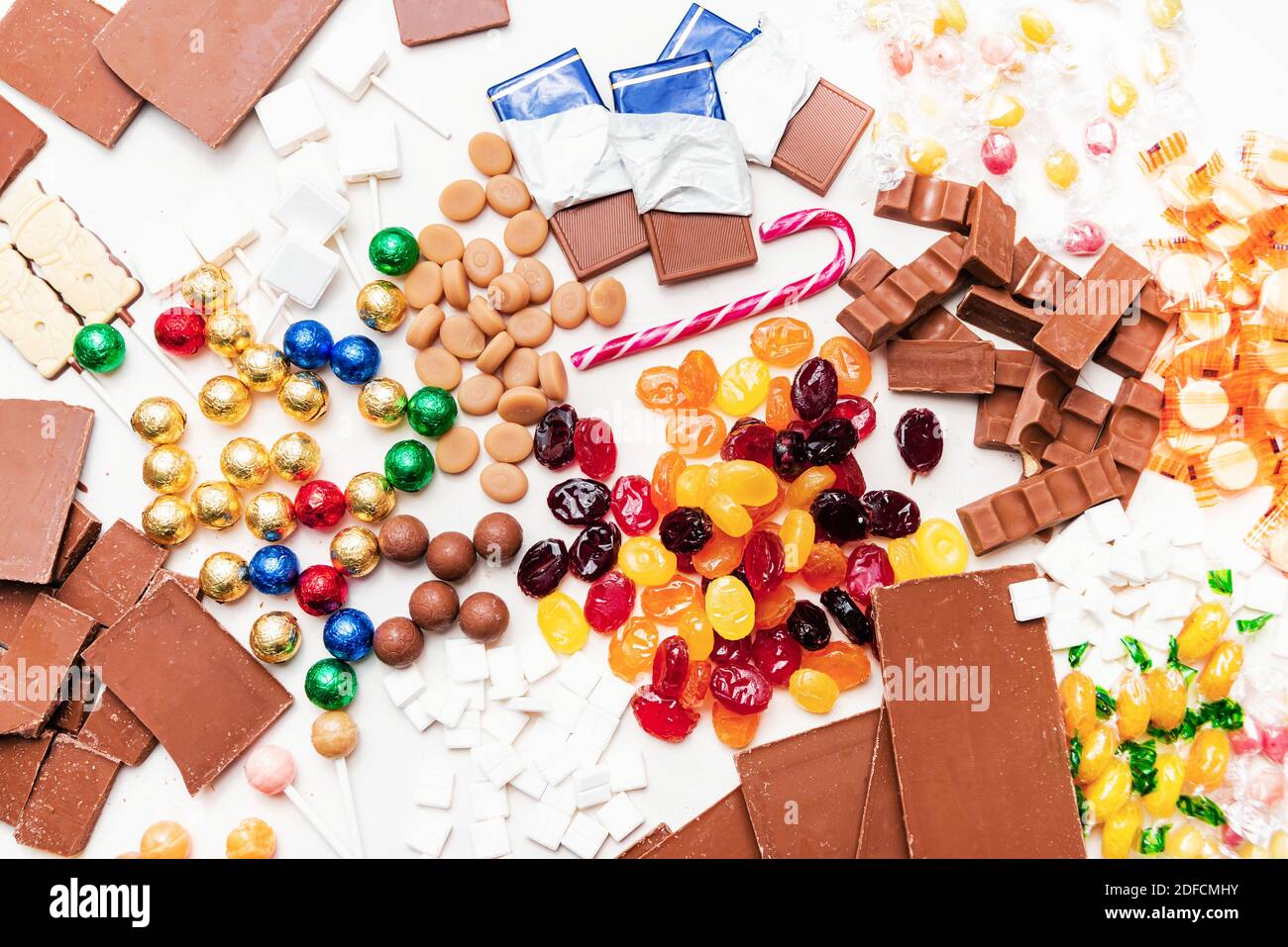 Top view photo of many sweets chocolate and caramels on white table ...