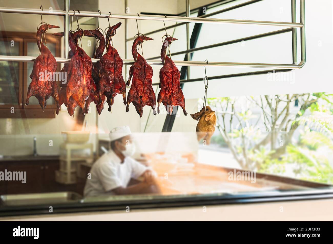 Cantonese duck and chicken on display in the window with chef in a ...