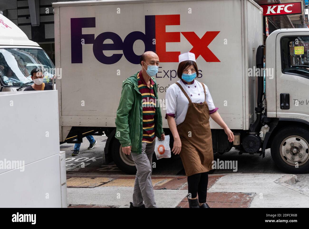 Pedestrians walk past an American FedEx Express delivery truck seen in ...