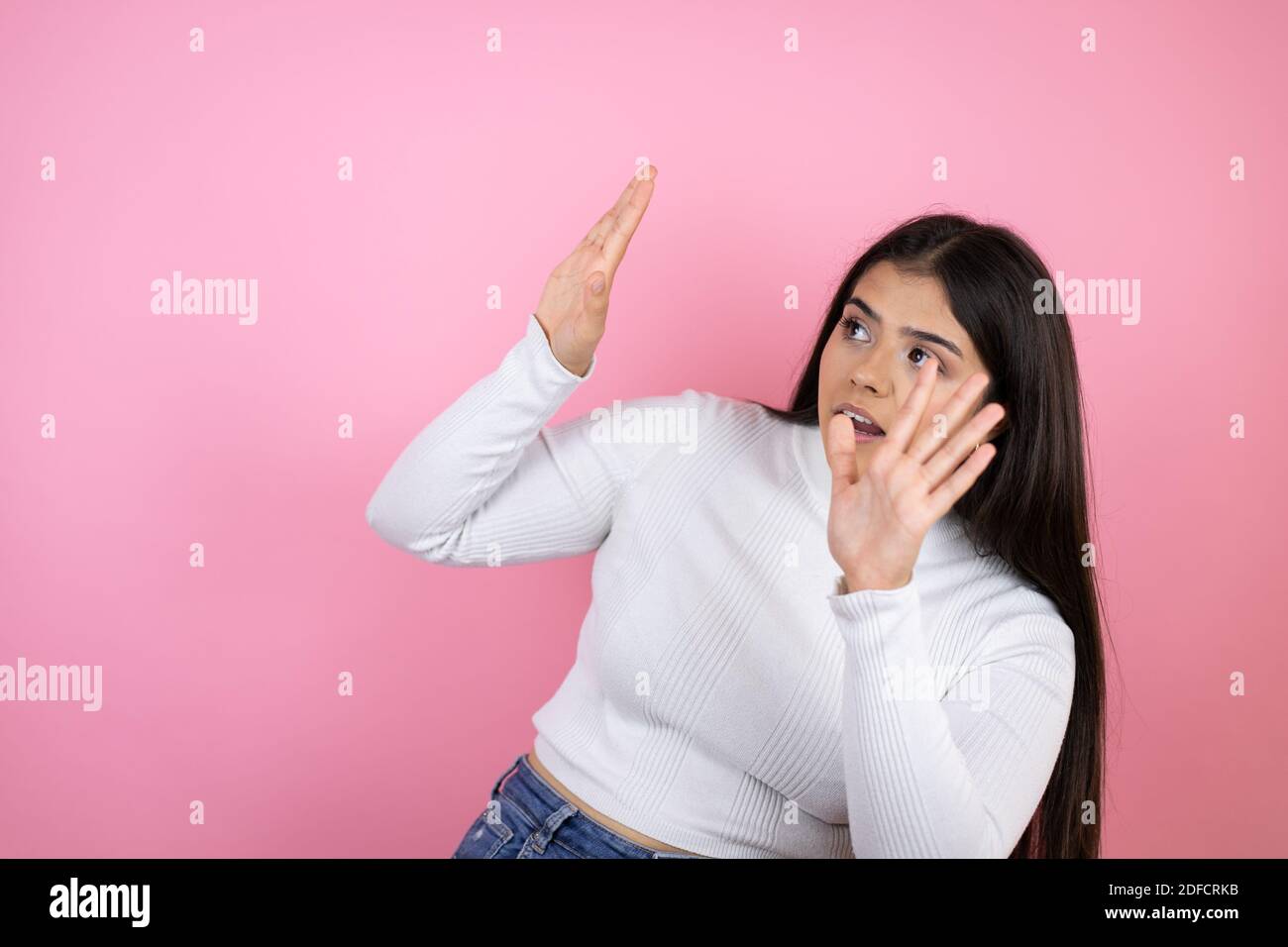 Young beautiful woman over isolated pink background scared with her ...