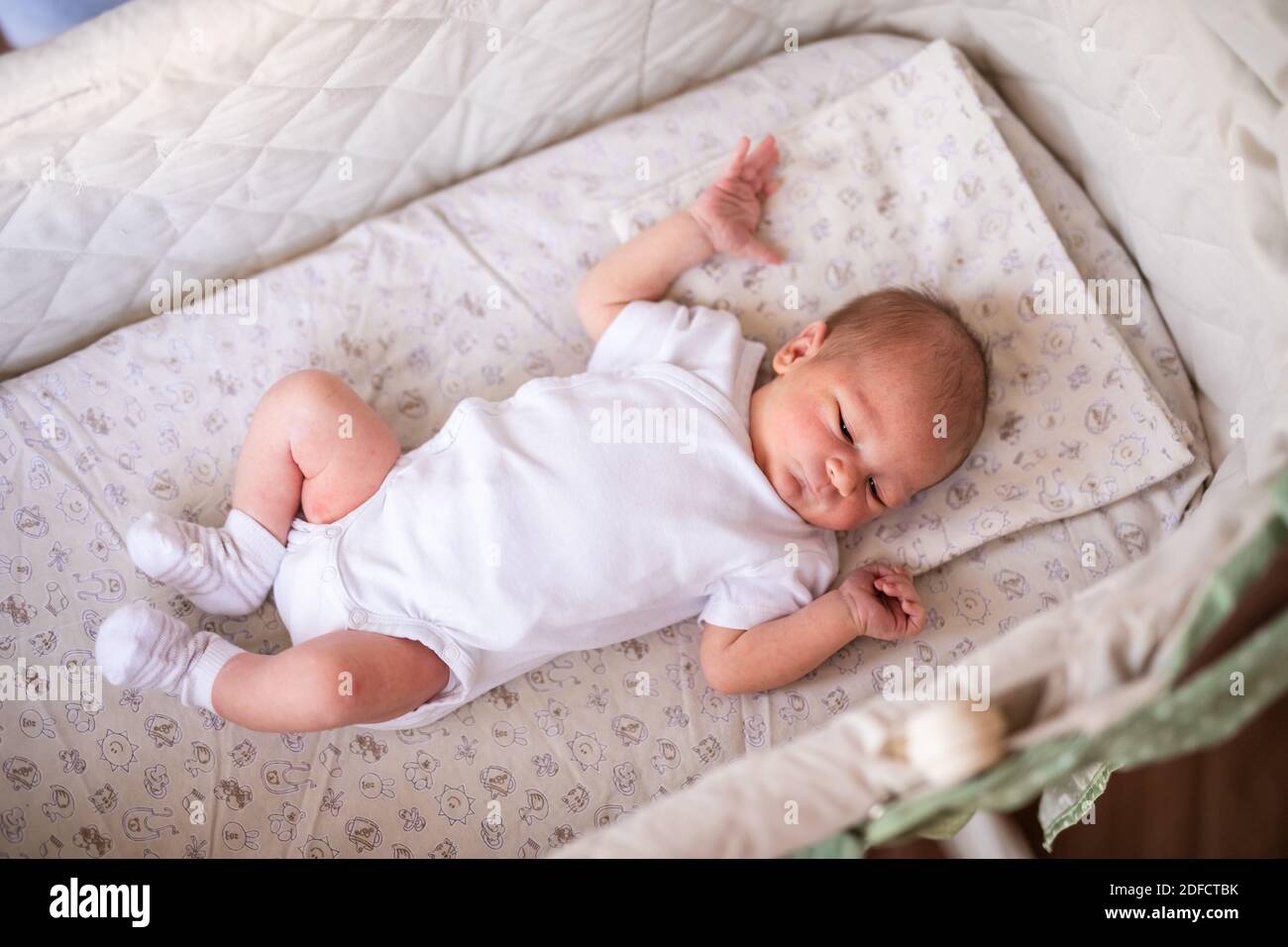 Newborn baby boy in bed. New born child in white bodykit lying in light ...