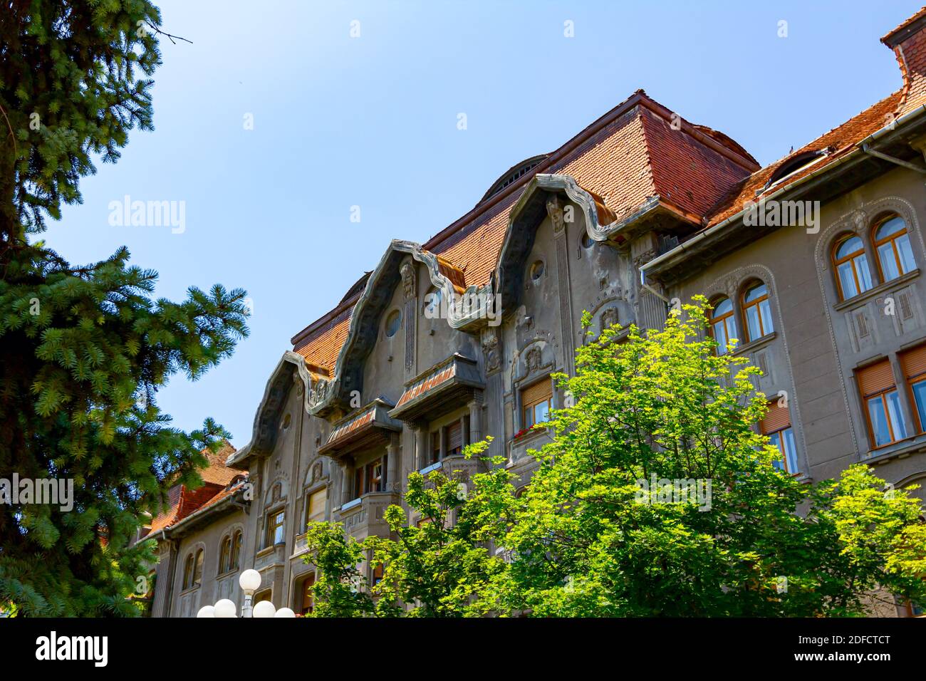 Bottom view is through the treetops on the decorated gray facade with ...