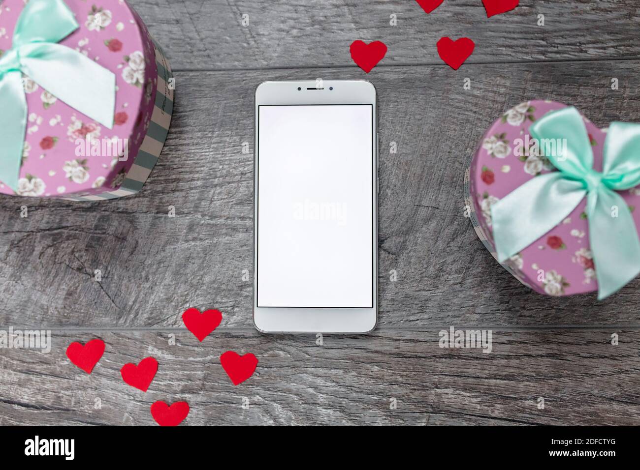 Valentine's day, phone on wooden grey background with red hearts and ...