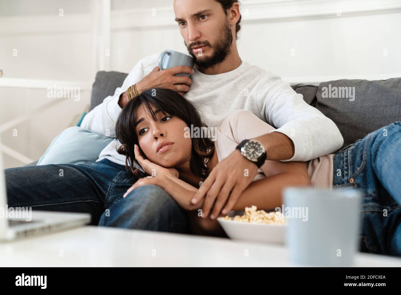 Photo of focused nice couple watching movie on laptop while resting on ...