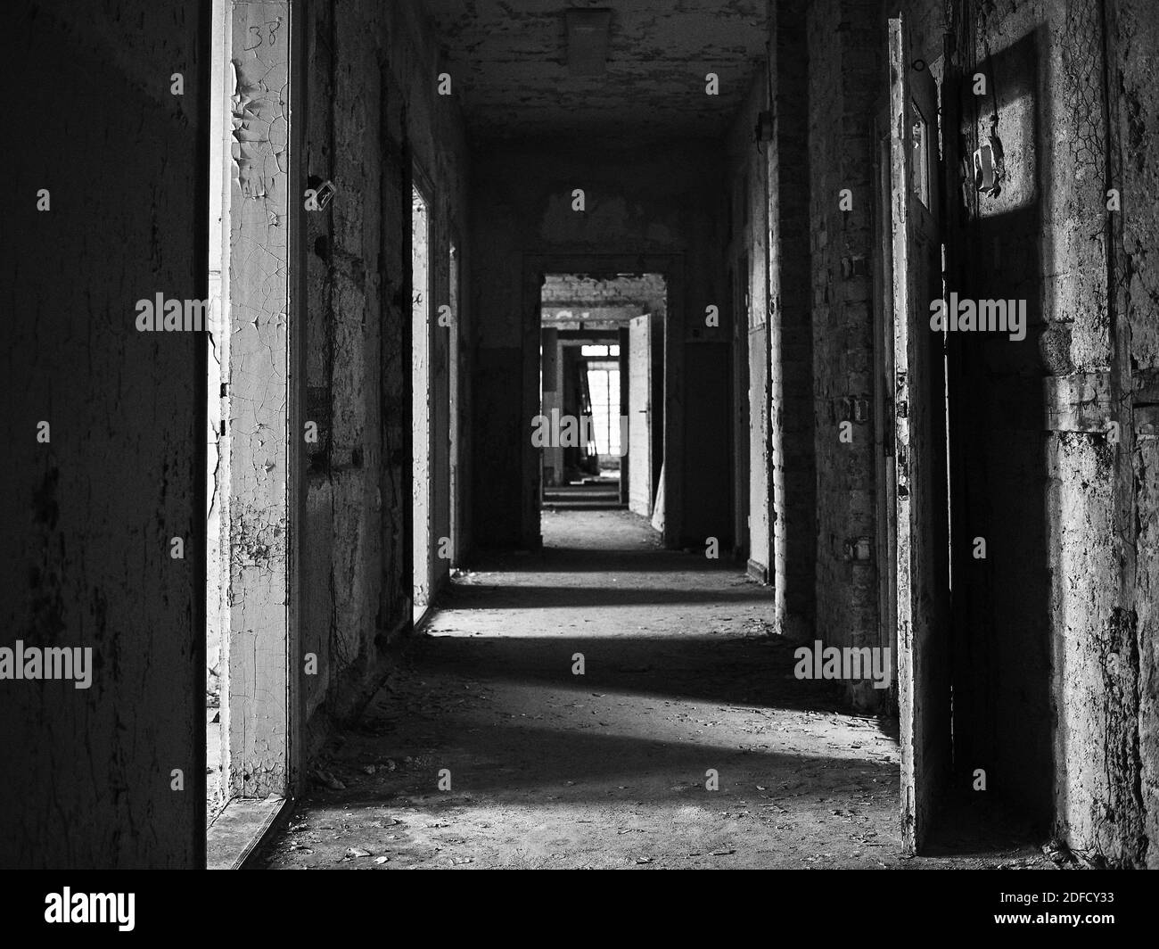 A greyscale shot of a creepy abandoned hallway inside of a building ...