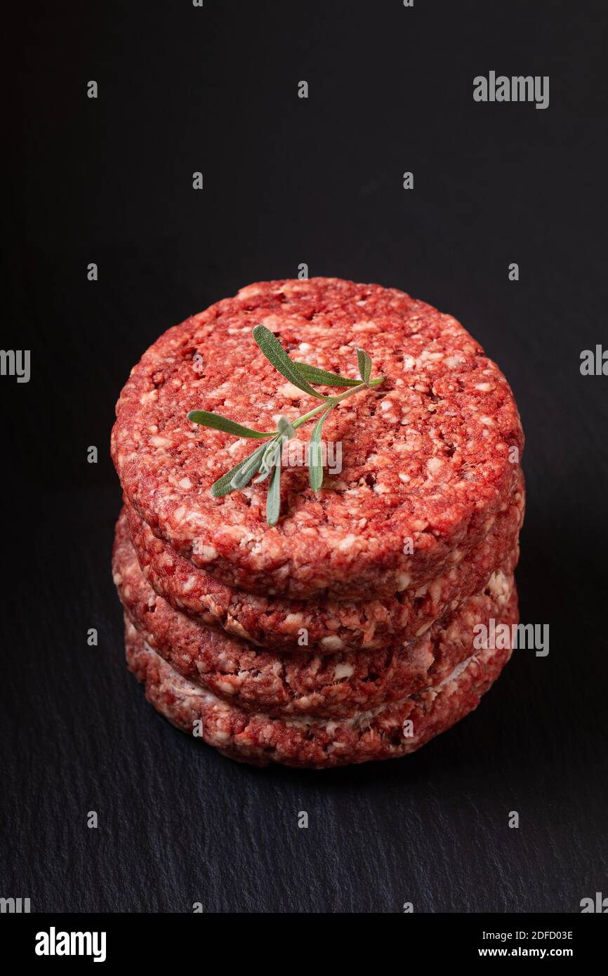 Food Concept Ground beef or hamburger beef patty stack on black slate ...