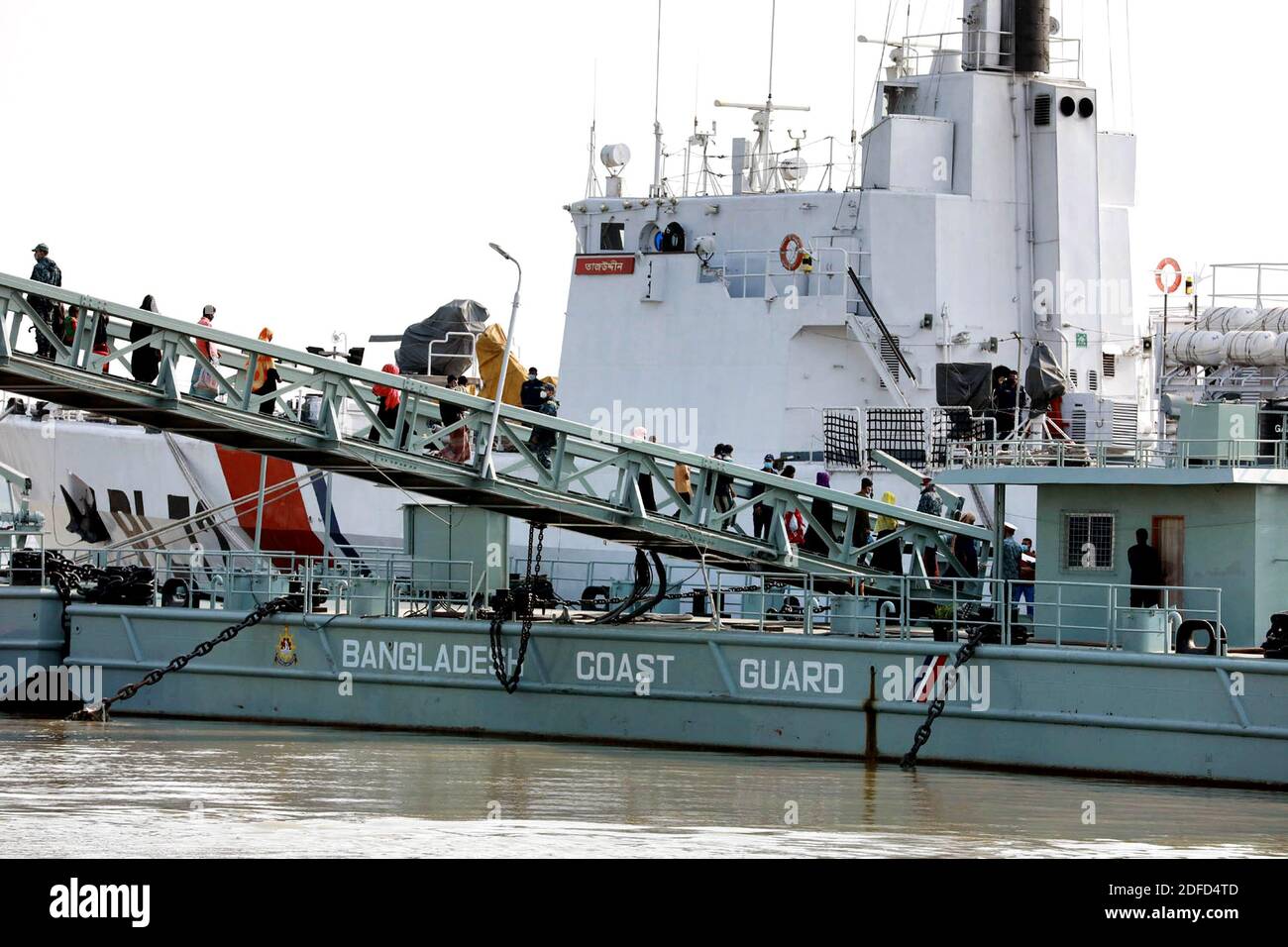 Rohingya refugees wait in a line to board a Bangladesh Navy ship to be ...