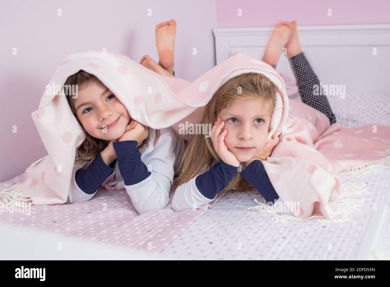 Little girls, sisters lying on their bed in pajamas covered with ...