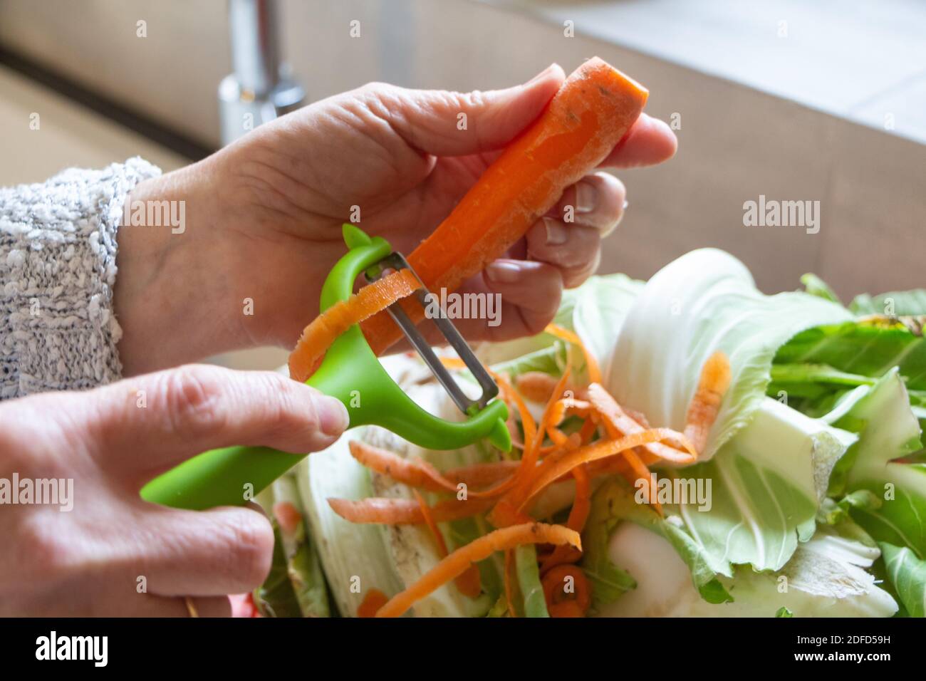 To peel a fresh carrot with a peeler Stock Photo - Alamy