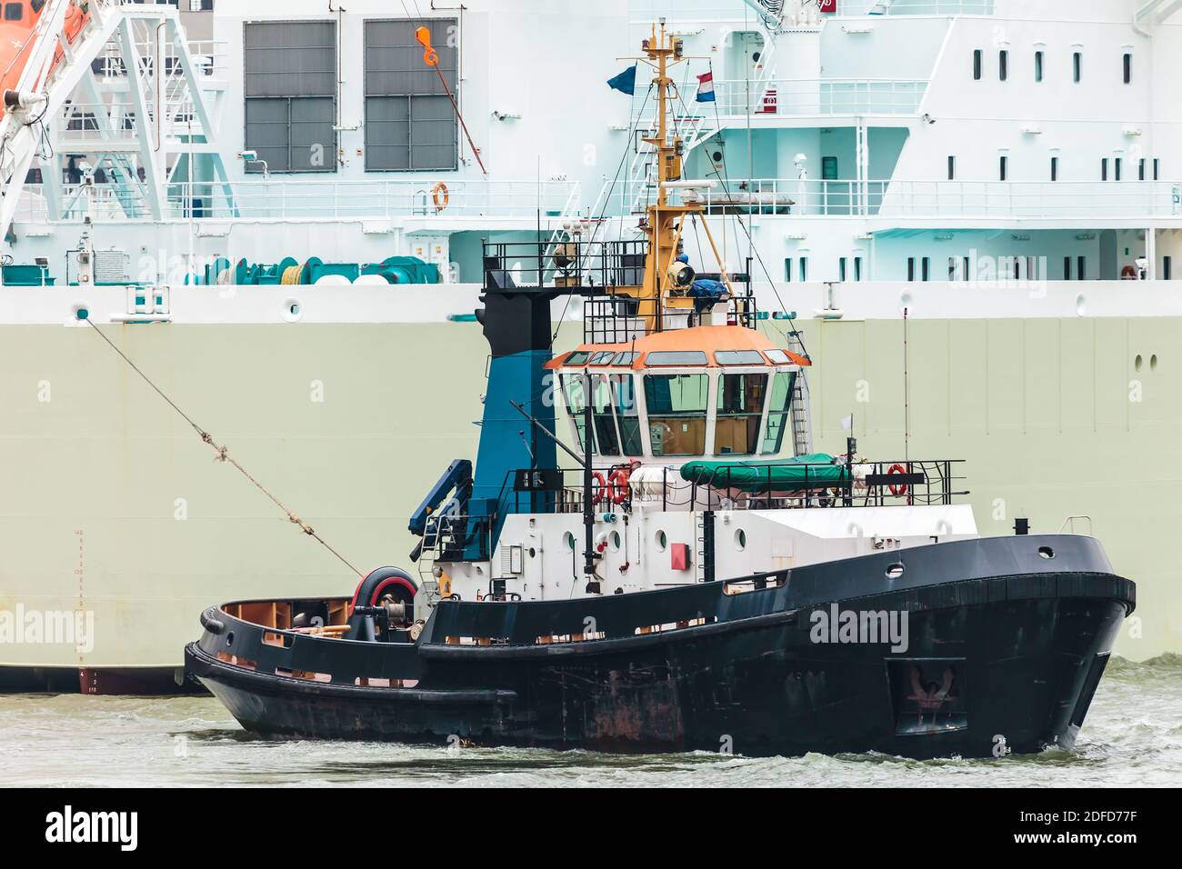 Tugboat pulling a large sea ship in the Dutch Rotterdam harbor Stock ...