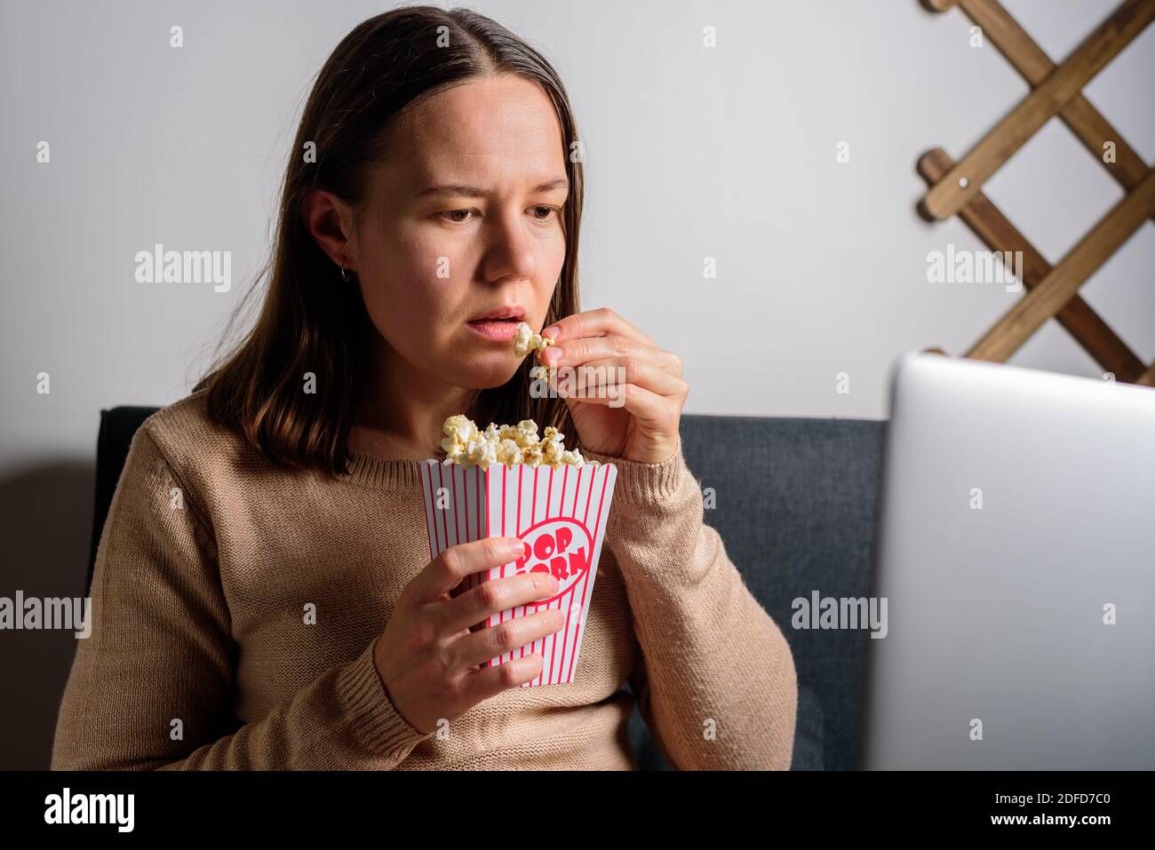 Woman shocked watching movie and eating popcorn Stock Photo - Alamy