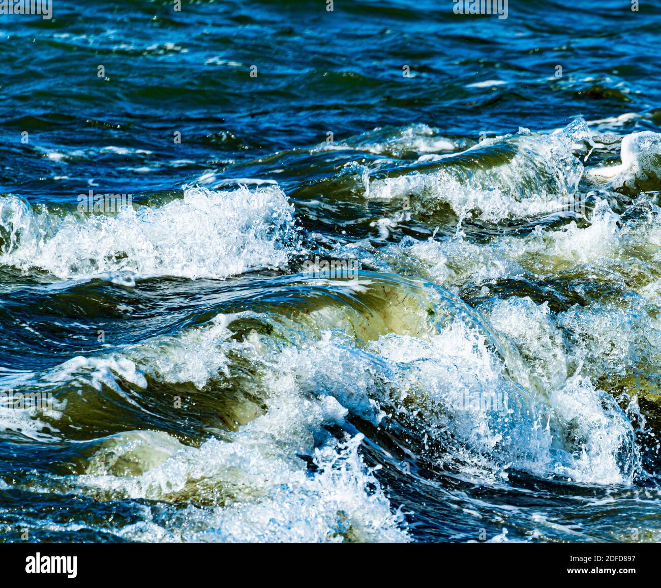 Roaring waves with foam, crashing onto rocks on a breakwater pier in a ...