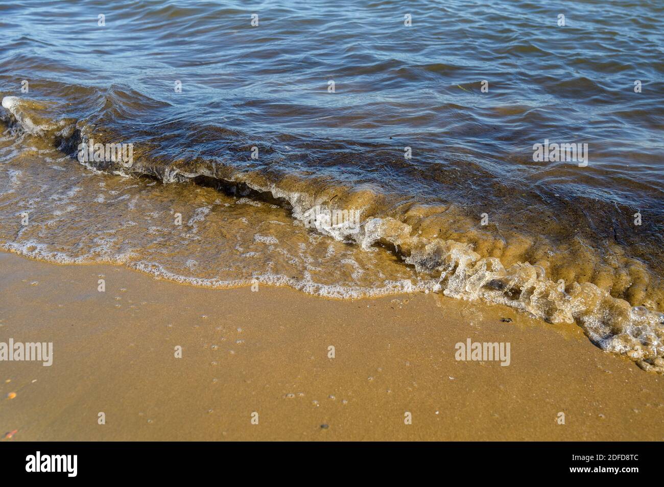 Waves at the seashore at sunset. Selective focus with shallow depth of ...