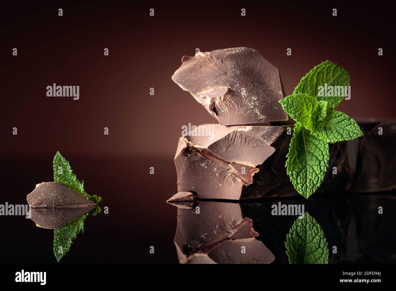 Large piece of dark bitter chocolate with mint on a black reflective ...