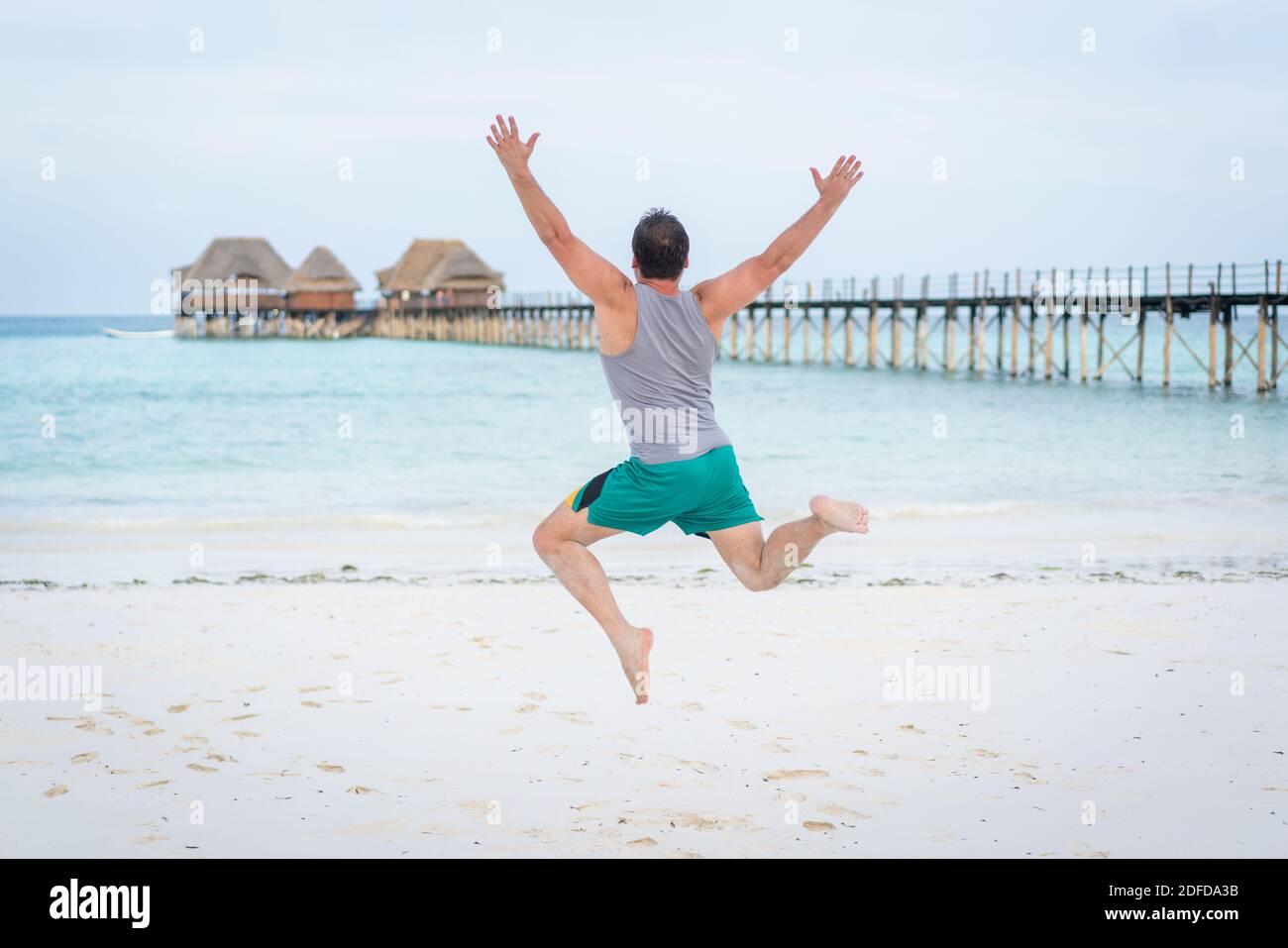 Jumping man on tropical beach Stock Photo - Alamy