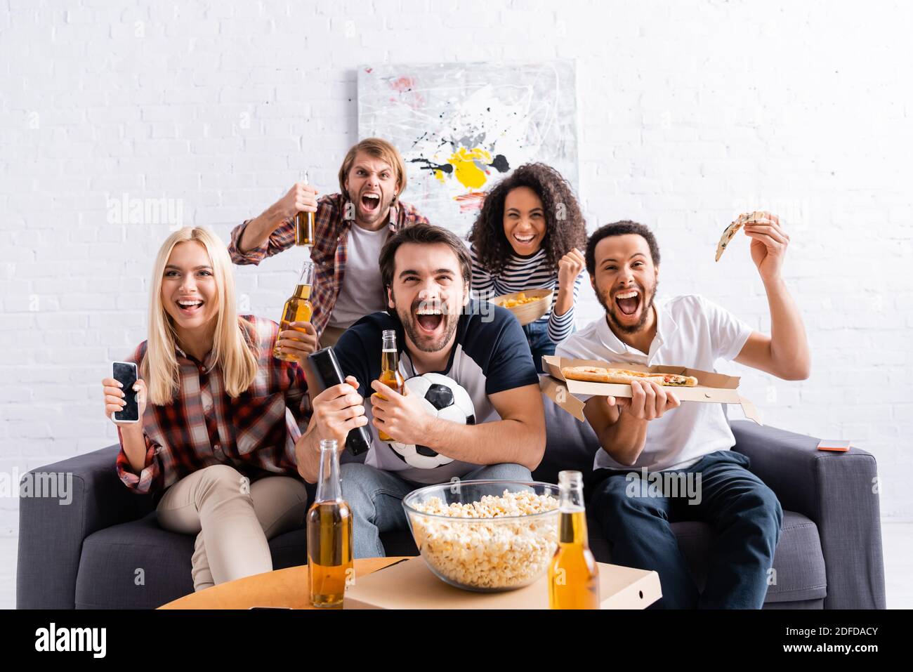 excited multicultural football fans shouting while watching ...