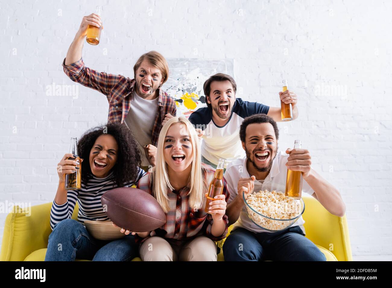 excited multiethnic friends with painted faces holding beer and ...