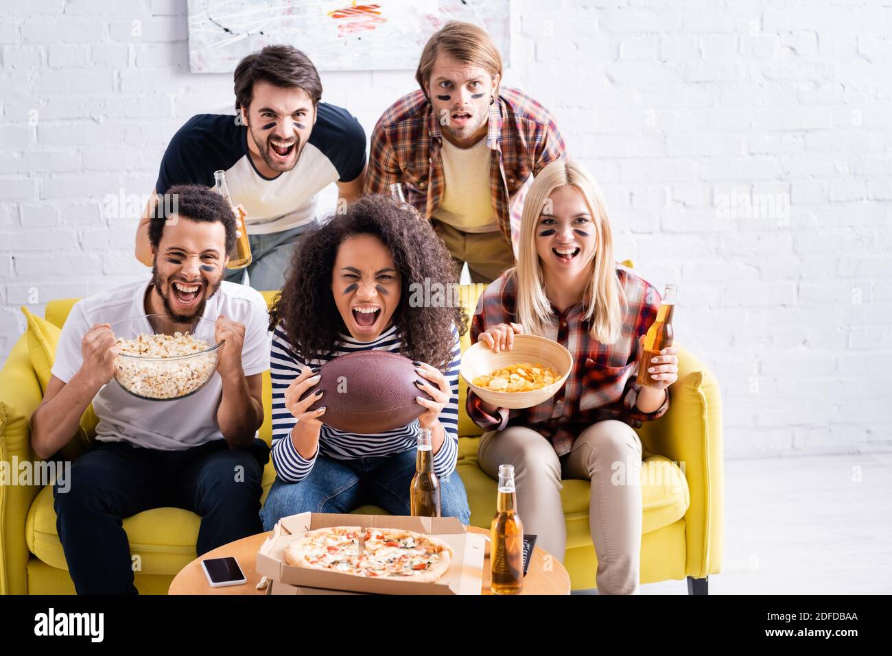 african american woman holding rugby ball and shouting while watching ...