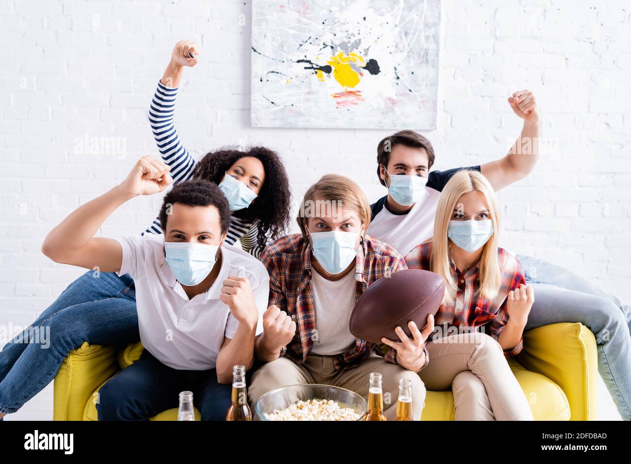 excited multicultural friends in medical masks showing win gesture ...
