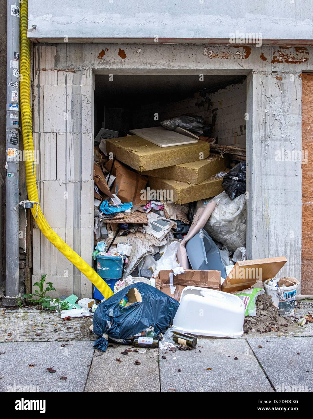 Rubbish & building debris overflowing onto pavement outside apartment ...