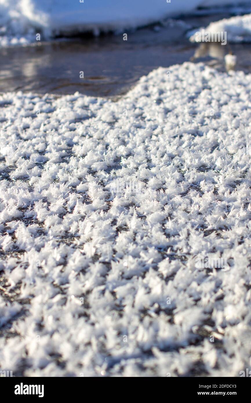 Ice crystals and white snowflakes near the water in winter. A cold ...