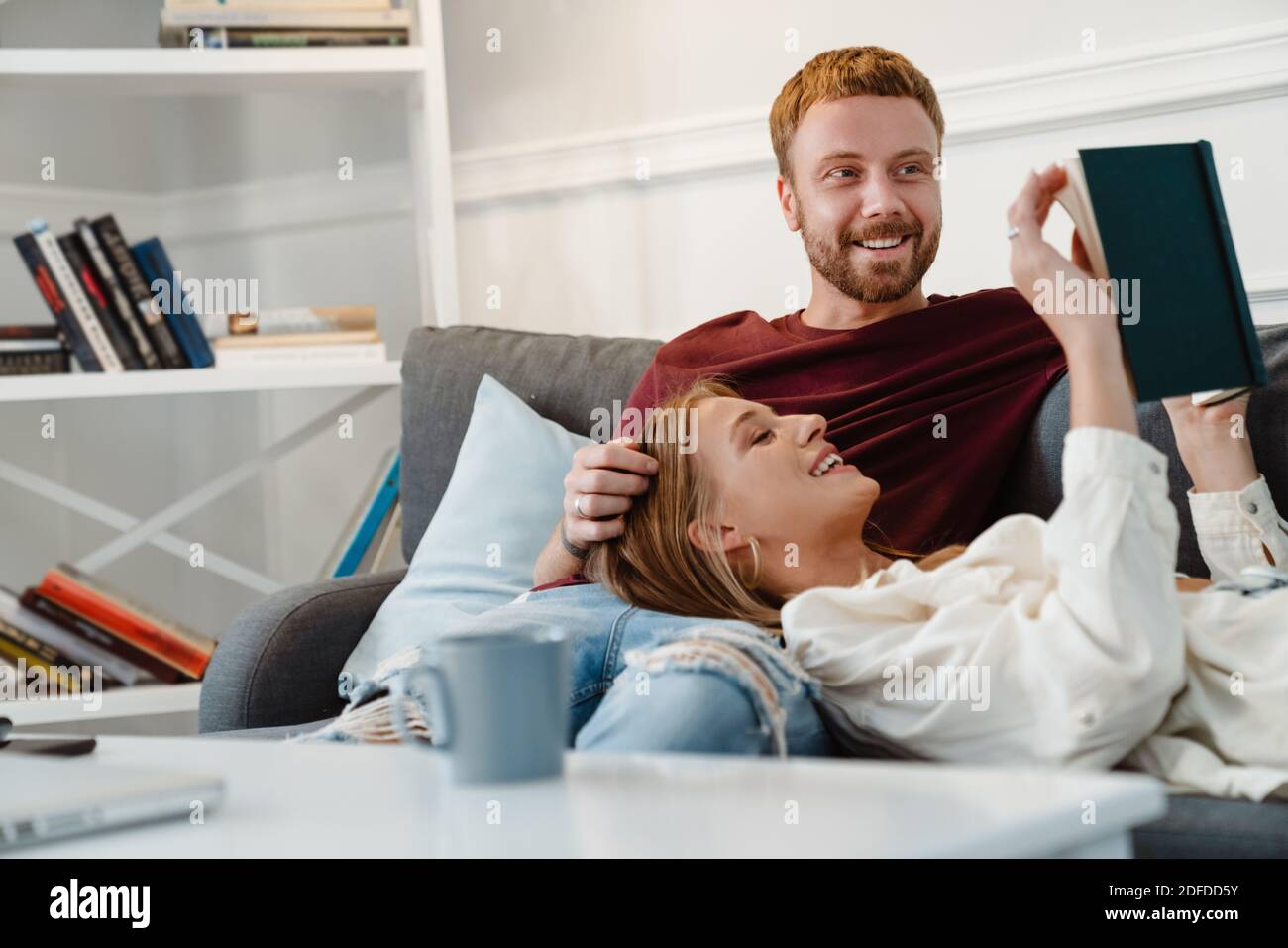 Photo of happy romantic couple hugging and reading book while resting ...