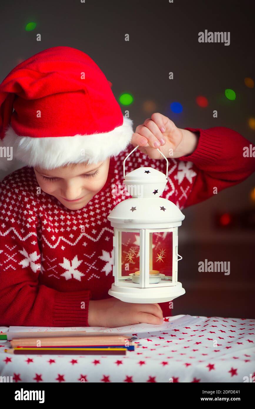 Christmas helper child writing letter to Santa Claus letter in red hat ...