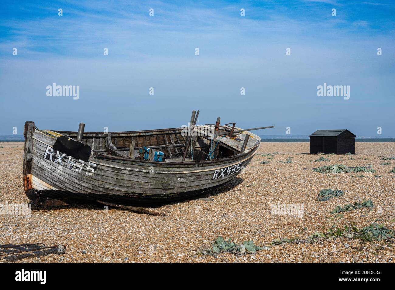 View of Dungeness with abndoned boat and hut Stock Photo - Alamy