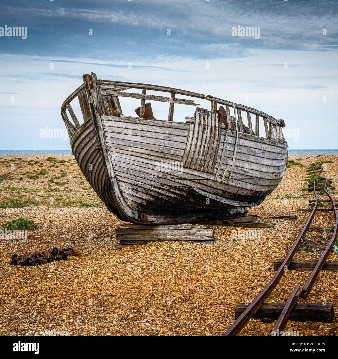 View of Dungeness with abndoned boat and railway line Stock Photo - Alamy