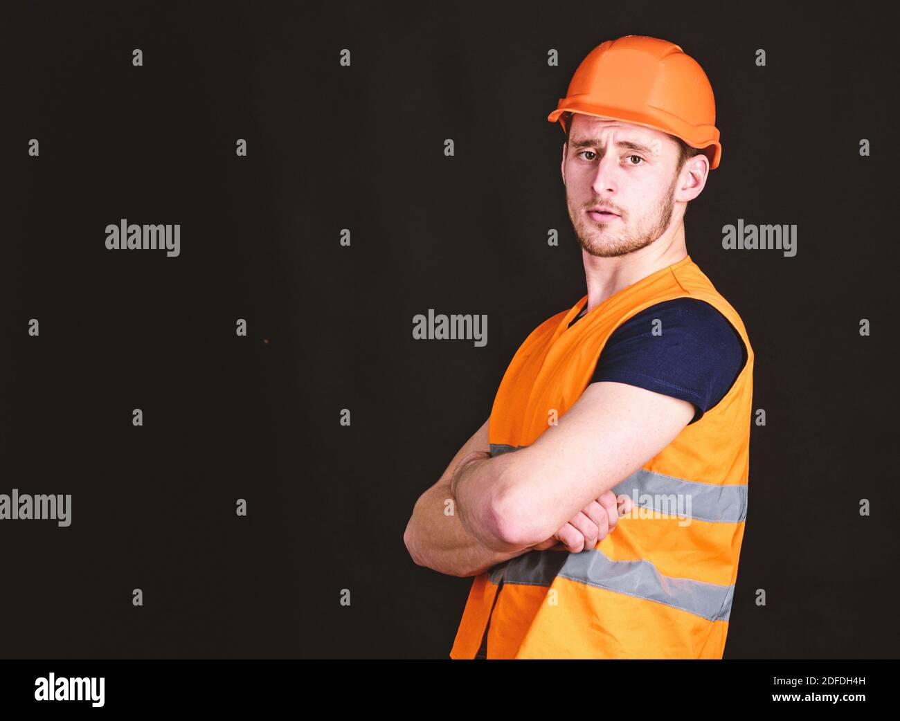 Strong builder concept. Man in helmet, hard hat hold arms crossed on ...