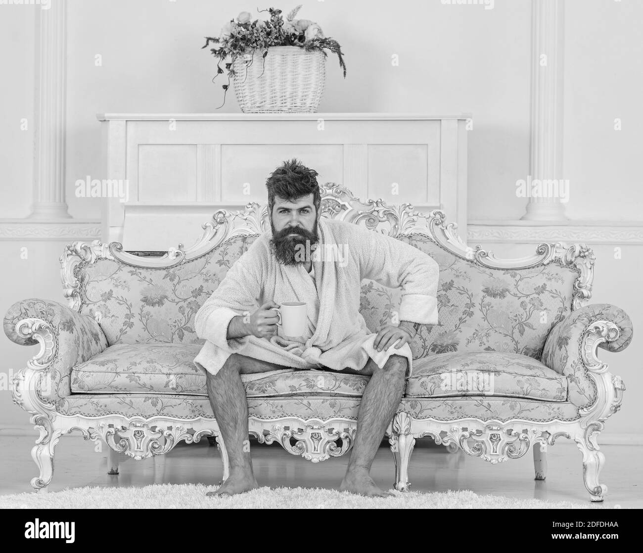 Man with beard and mustache enjoys morning while sitting on luxury sofa ...