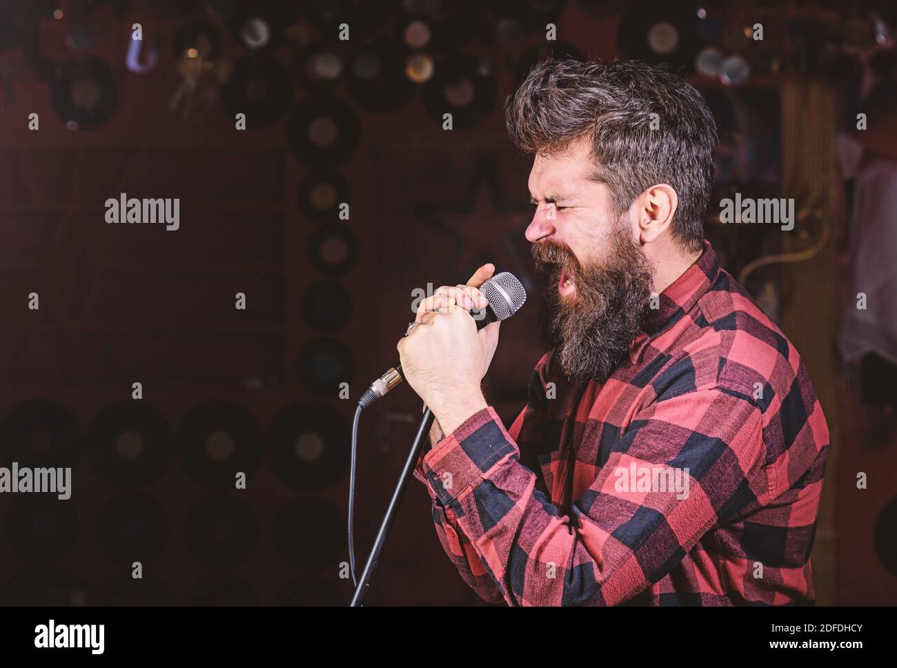 Man with tense face holds microphone, singing song, black background ...