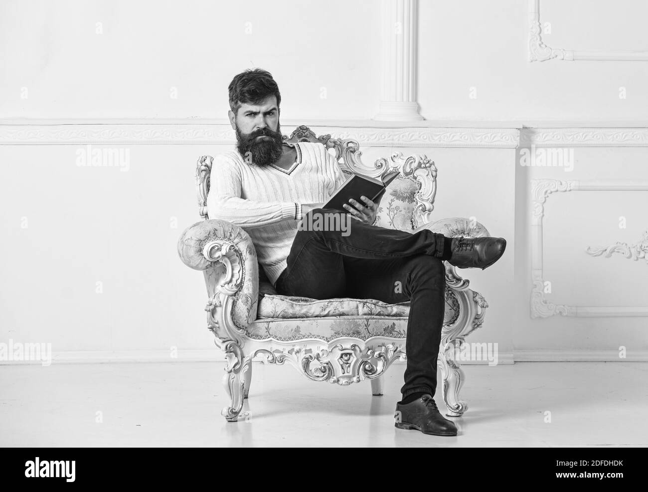 Man with beard and mustache sits on armchair and reading book, white ...