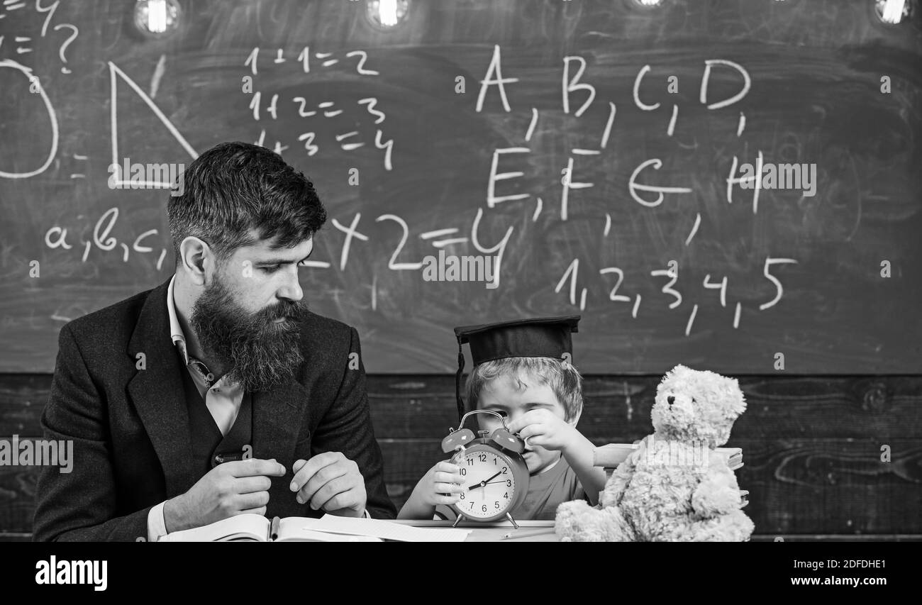 Teacher with beard, father teaches little son in classroom, chalkboard ...