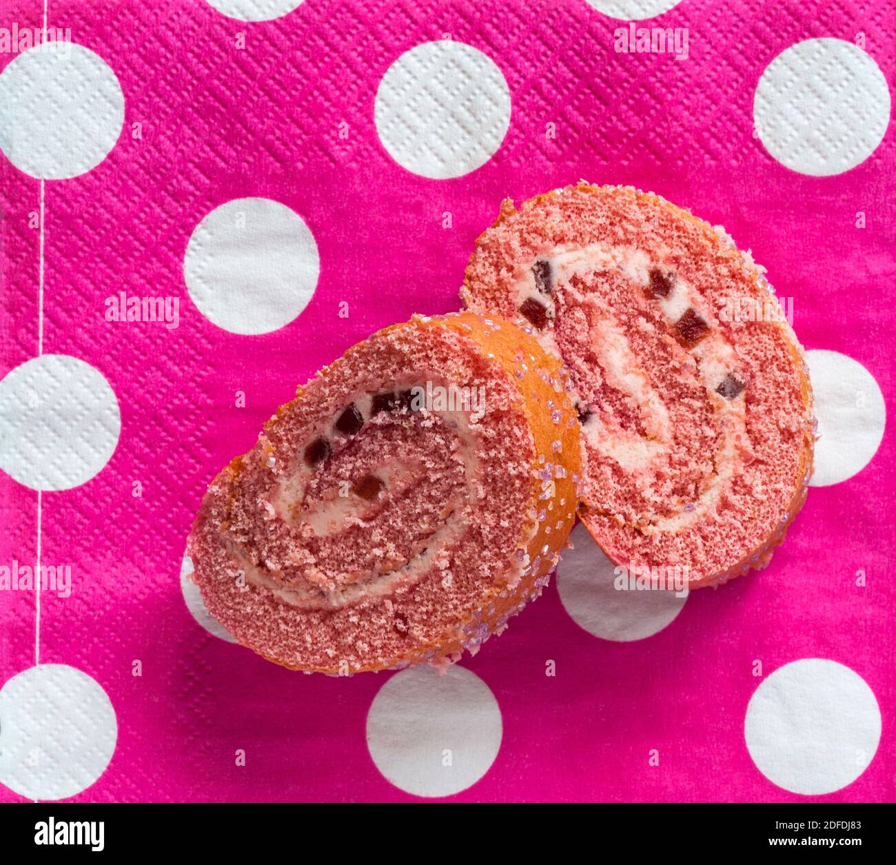 Slicec of M&S Percy Pig sponge roll cake set on serviette napkin - pink ...