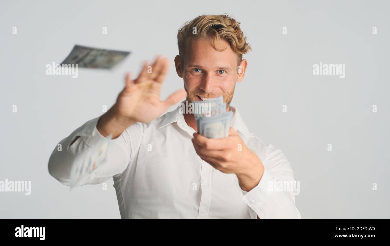 Handsome excited bearded businessman happily throwing money into camera ...