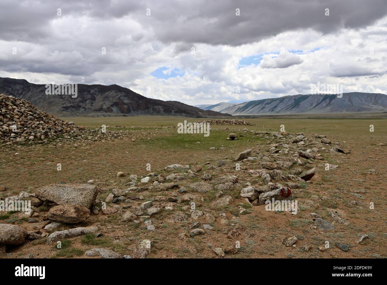 A Landscape of a deserted area surrounded by hills under a cloudy sky ...