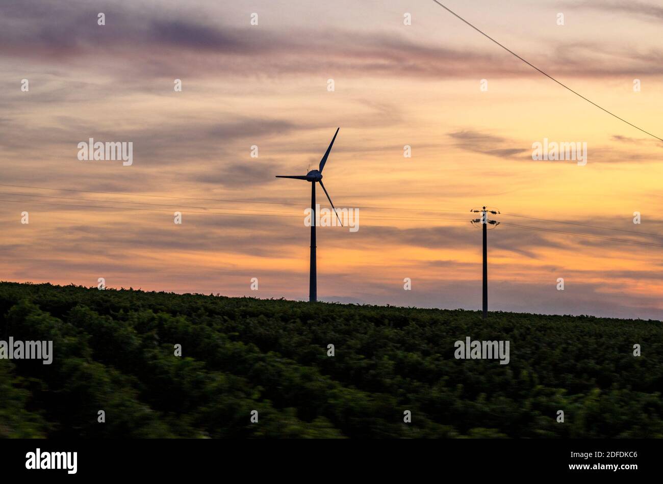 Wind turbine and high voltage pylon in the countryside at sunset Stock ...