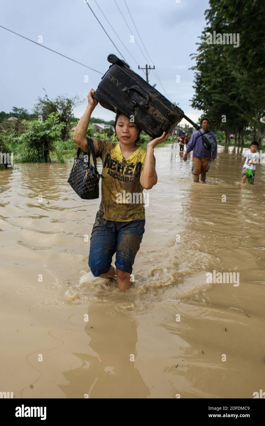 People walk through a submerged road.Over 12,338 residents have been ...