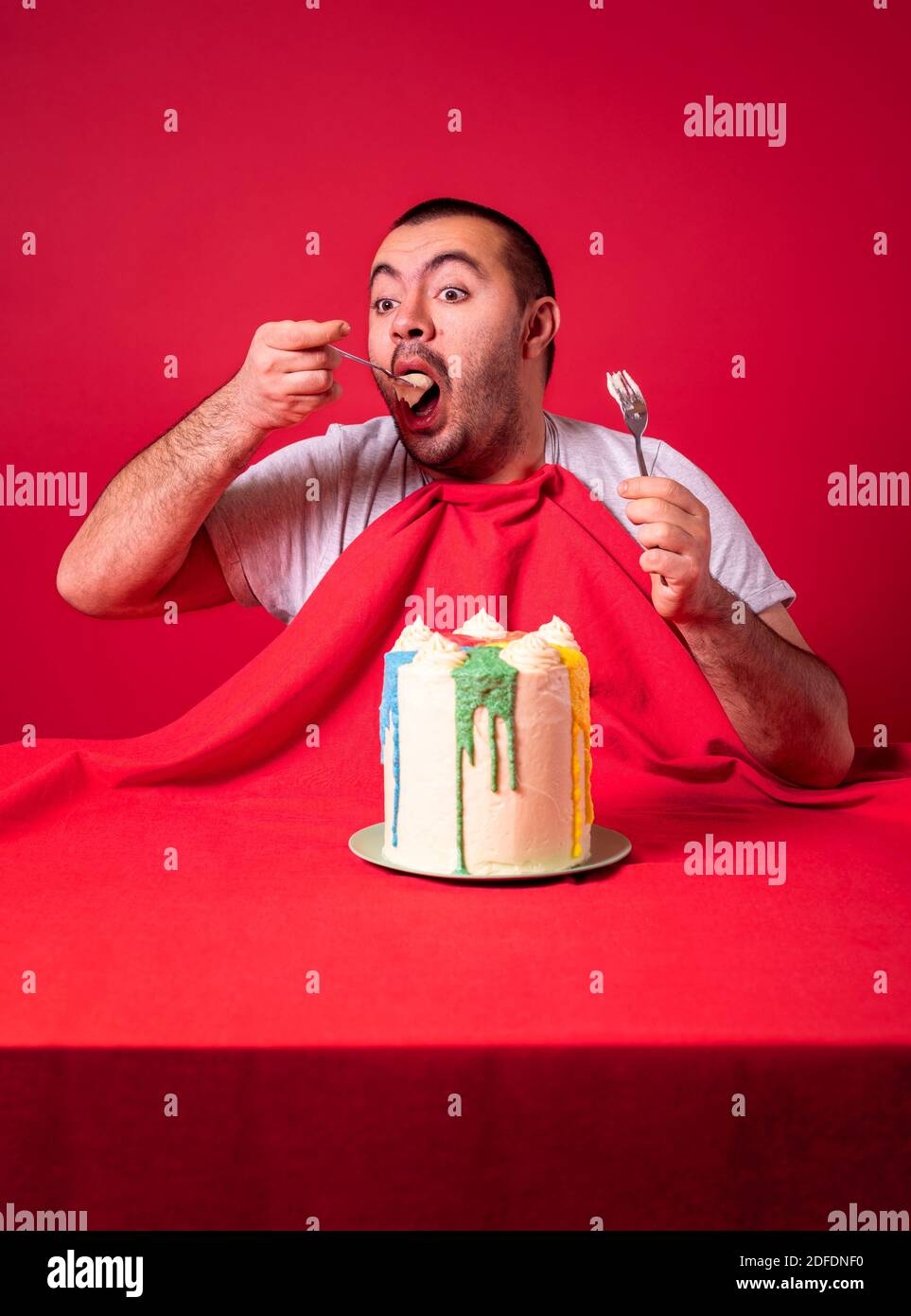Young man eating all by himself huge birthday cake. Hungry man eating ...