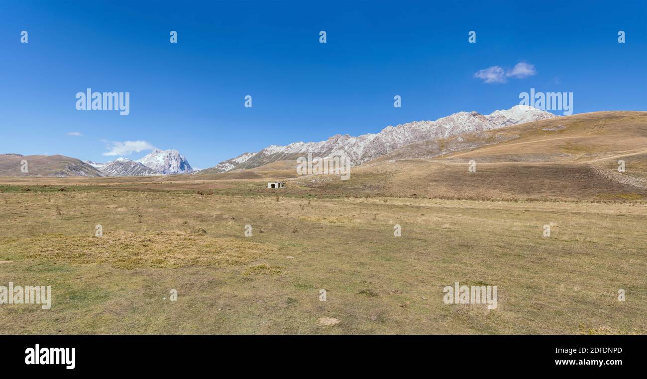 panoramic landscape with upland mild green slopes below Rocky range ...