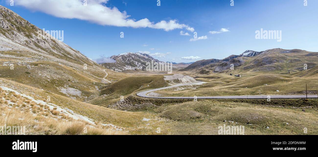 panoramic landscape with road bending downhill on barren slopes at flat ...