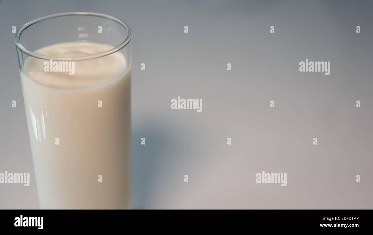 pour yogurt into a glass a transparent stream of kefir white background ...