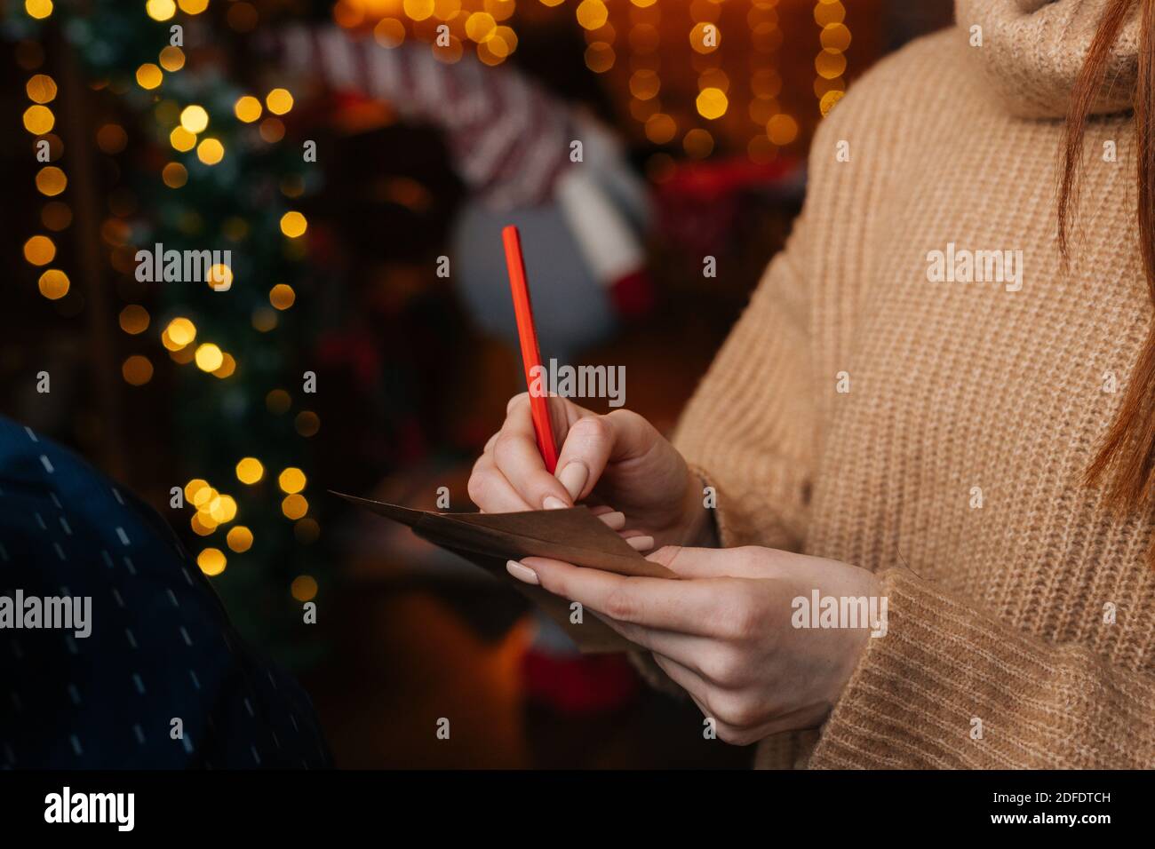 Close-up hands of young woman writing Christmas letter to Santa Claus ...