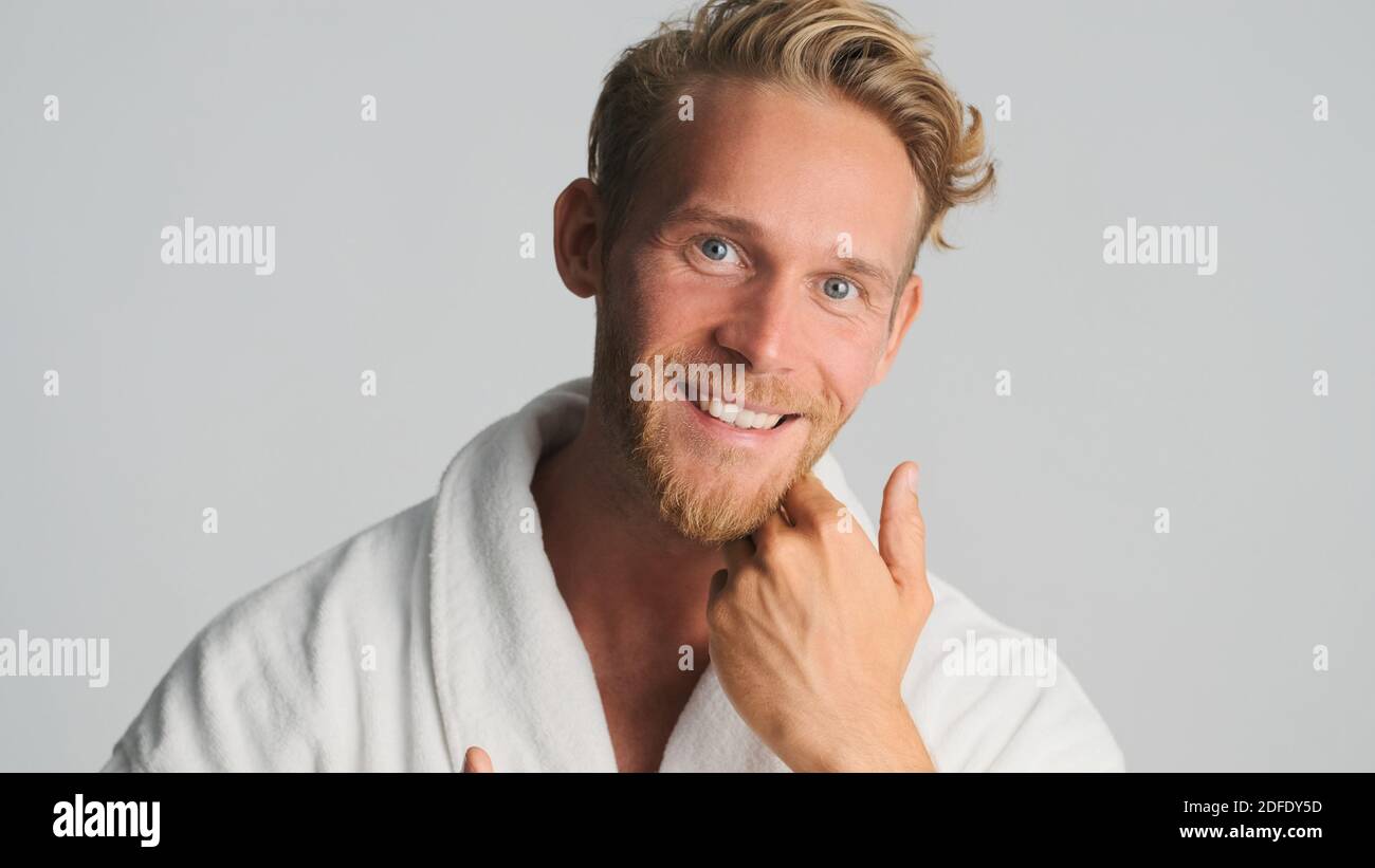 Attractive Bearded Man In Bathrobe Joyfully Posing On Camera Over White