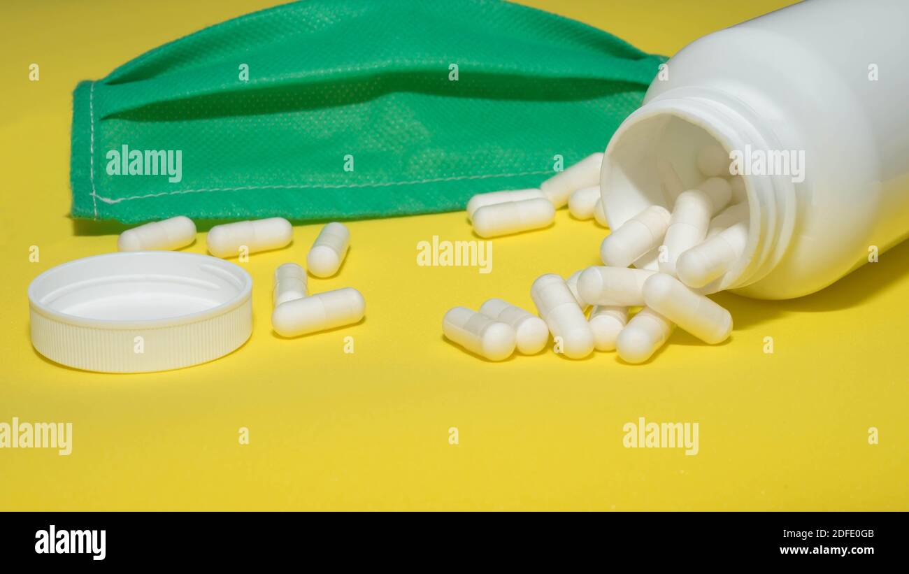 Medical face mask.Close-up,of capsules poured from a jar on a yellow ...