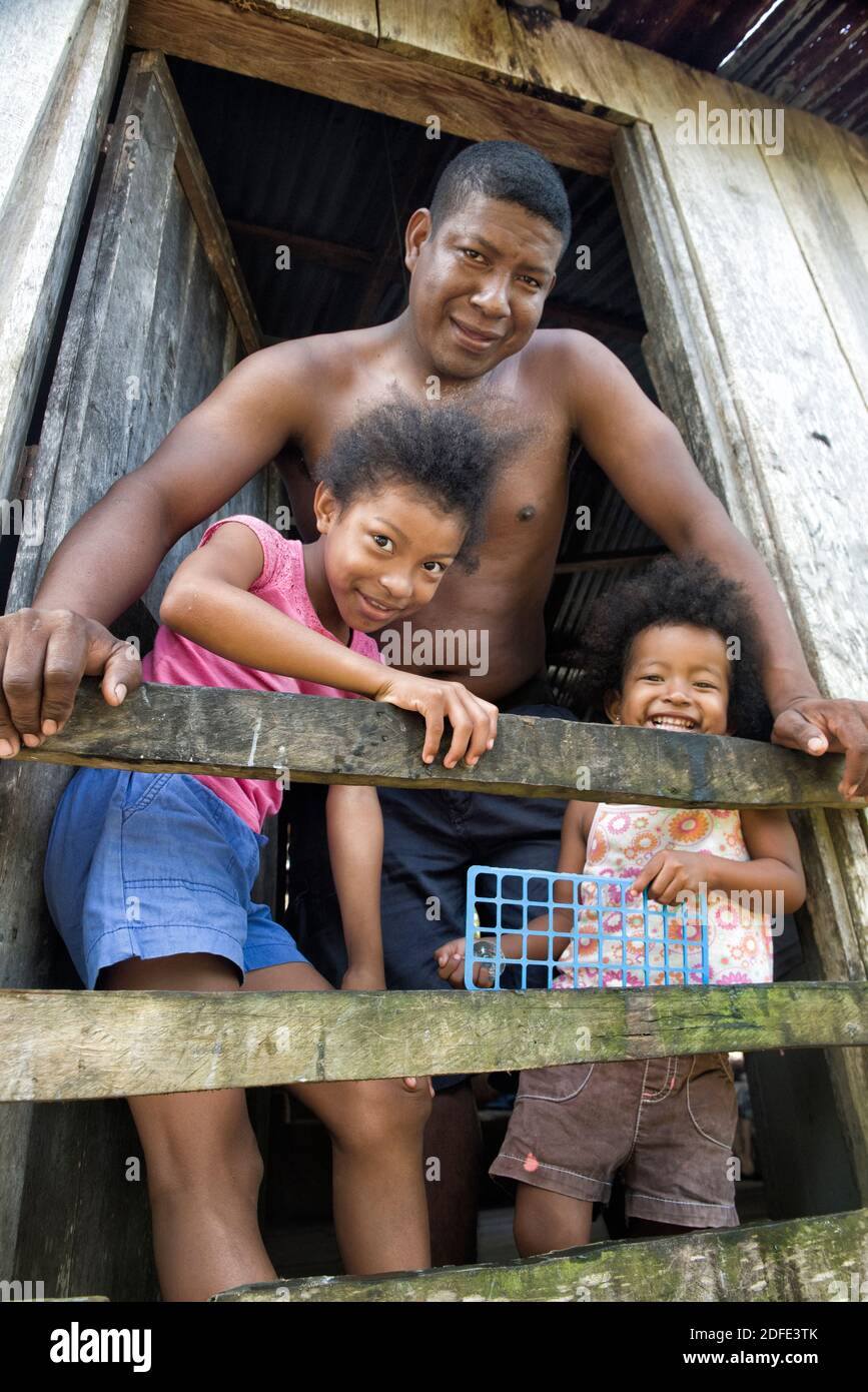 Indigenous father with children looking out his shack window.Raista ...