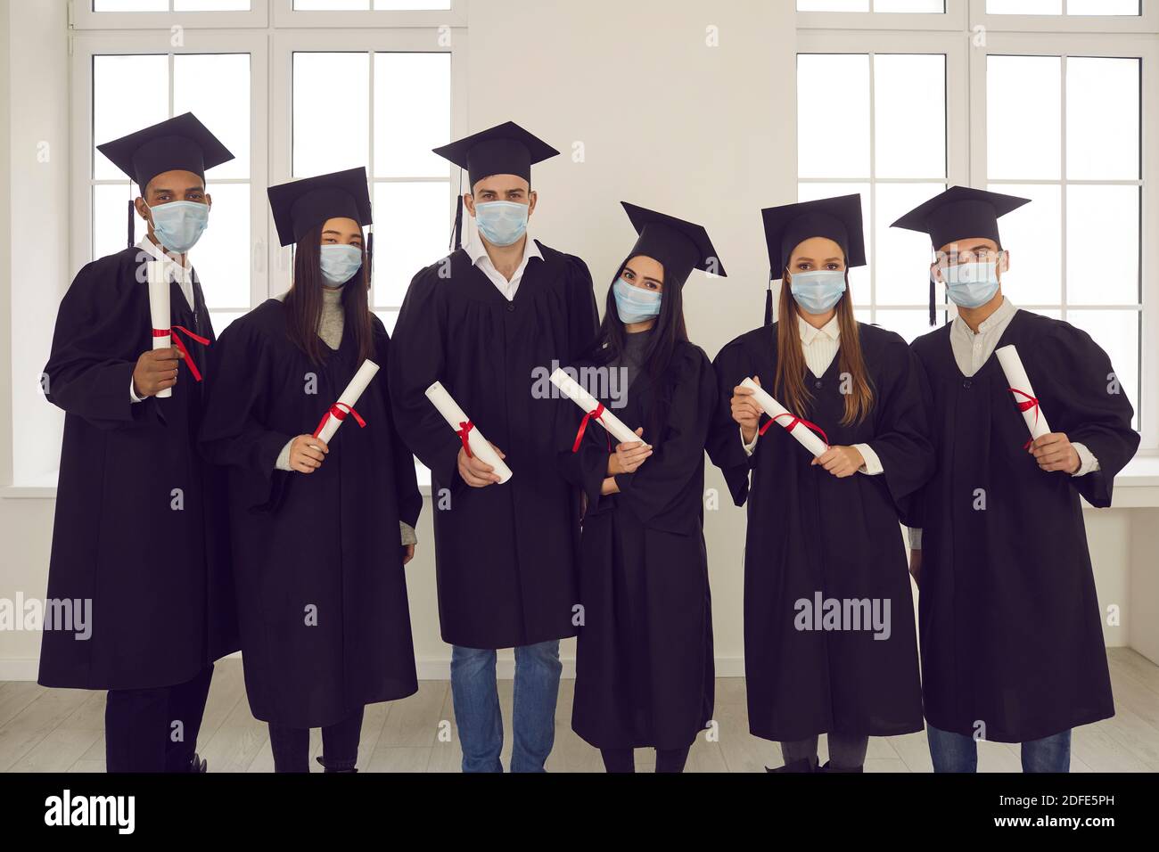 Group portrait of multiethnic university graduates in face masks ...