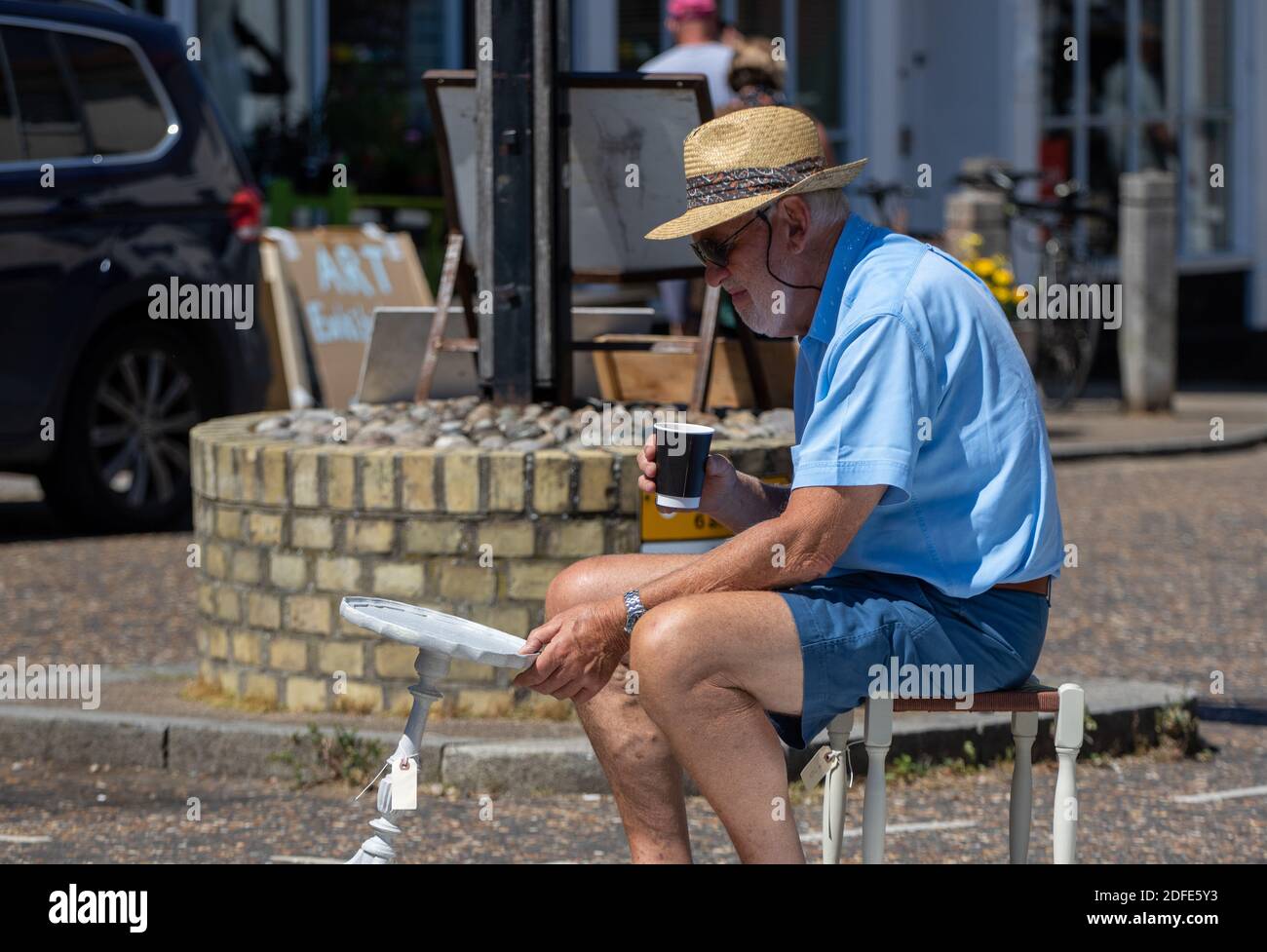Older male stall holder sitting in the sun with a coffee Stock Photo ...